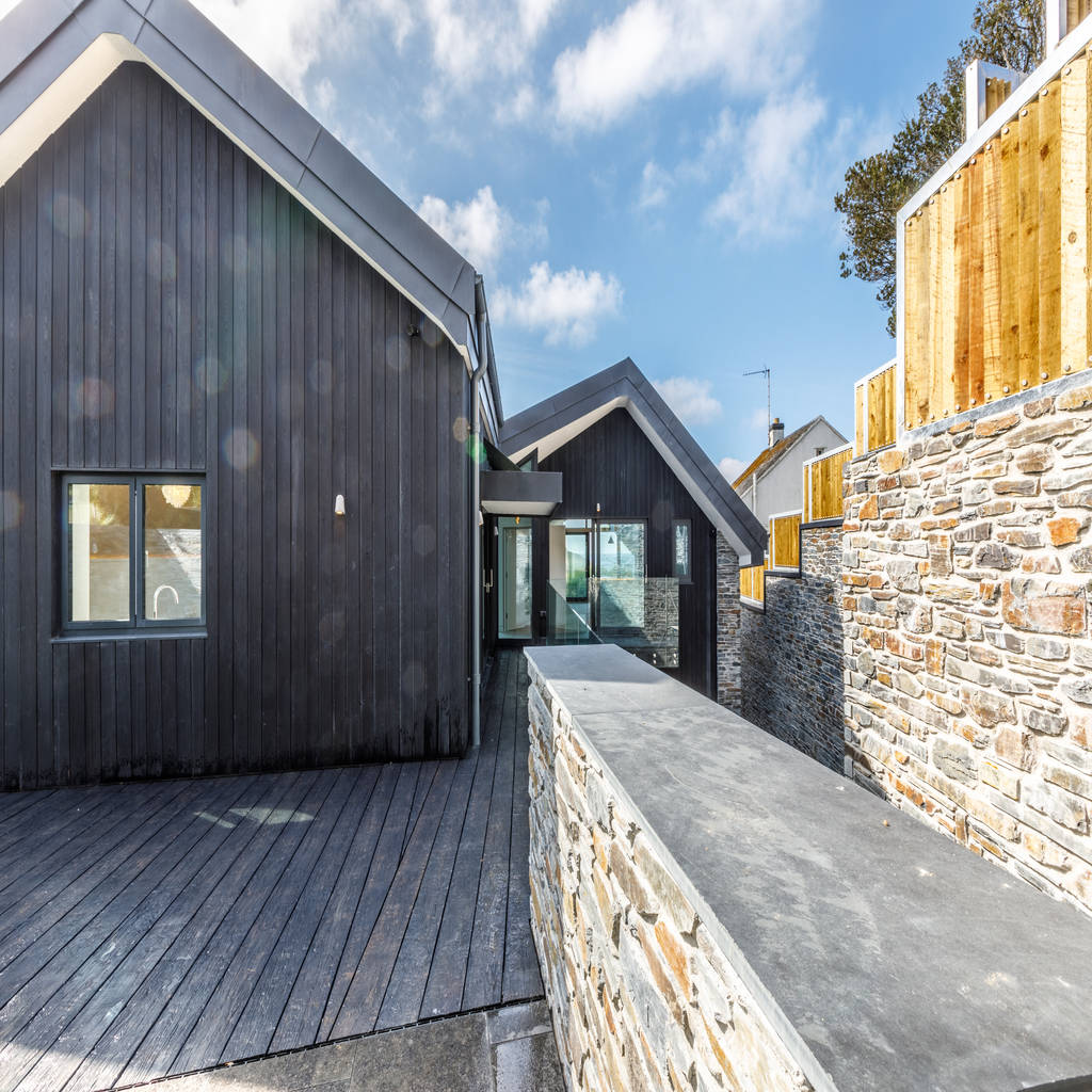 Black timber clad building with black composite timber decked area and ...